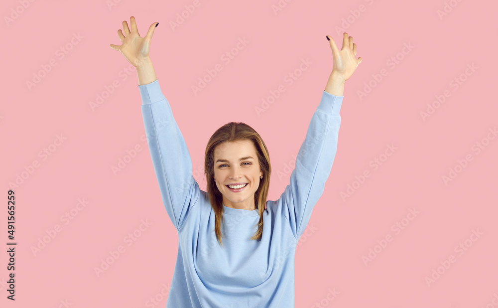 Studio shot of a happy joyful young woman raising her arms and smiling ...