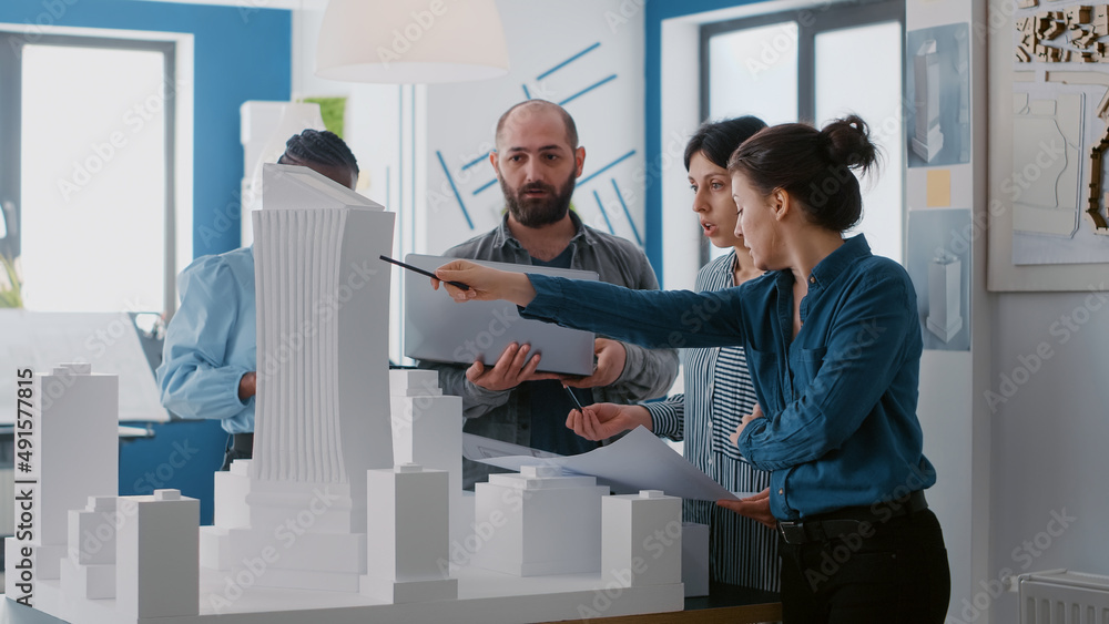 Multi ethnic people working with laptop, tablet and building model for ...