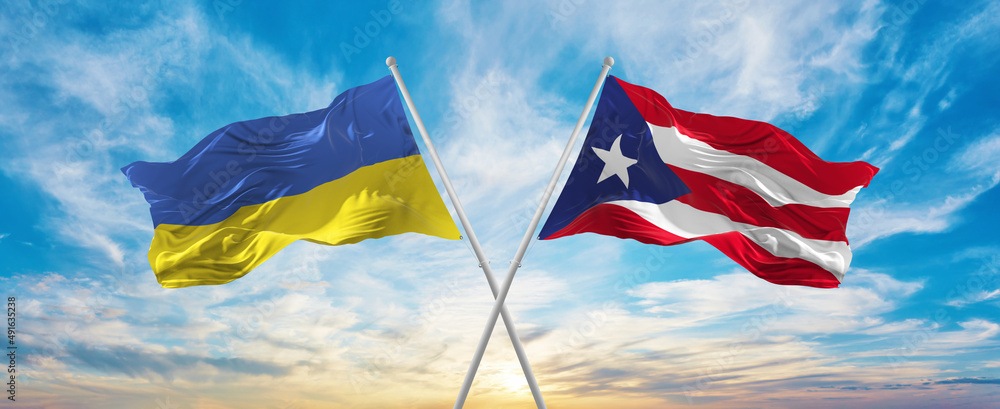 crossed national flags of Ukraine and Puerto Rico flag waving in wind ...