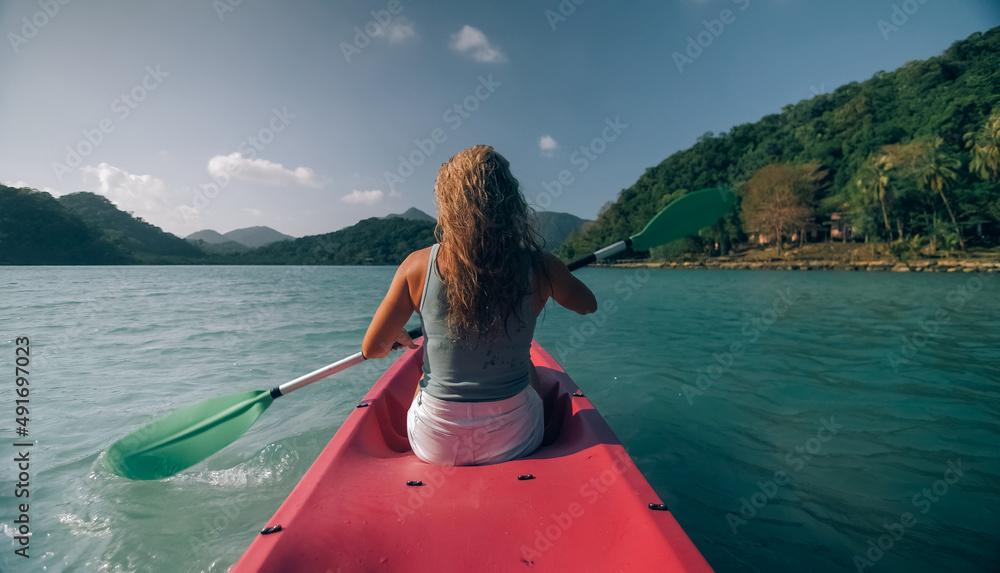 Long haired blonde woman with sunglasses rows bright pink canoe along ...