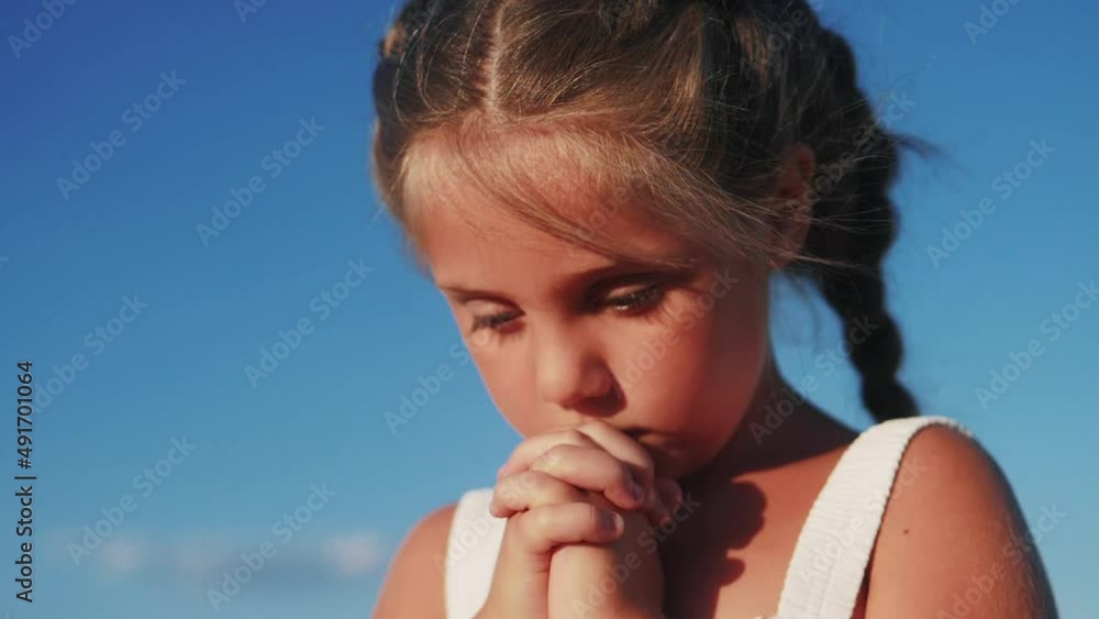 Video Stock girl kid pray against a blue sky. child close-up concept ...