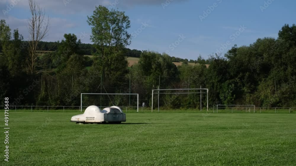 White battery-powered robotic lawn mower cutting green grass on a ...