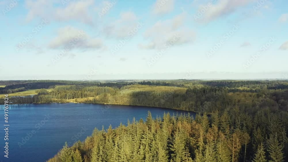 Scene from Danish forest with view past silhouette trees to a shiny ...