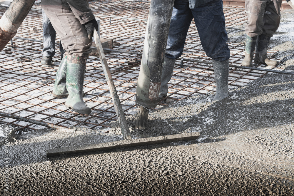 Builders workers pour concrete floor in industrial workshop. Legs in ...
