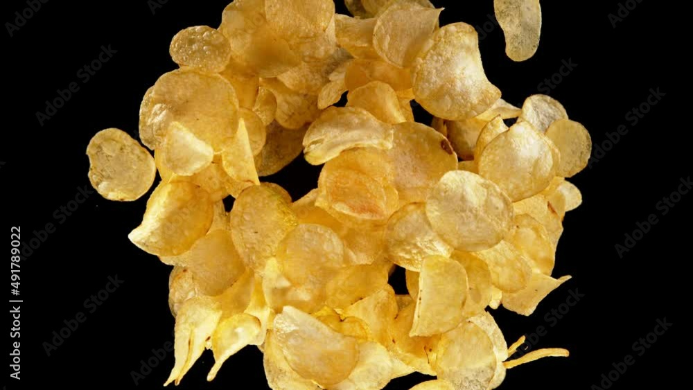 Super slow motion of rotating fried potatoes chips on black background ...