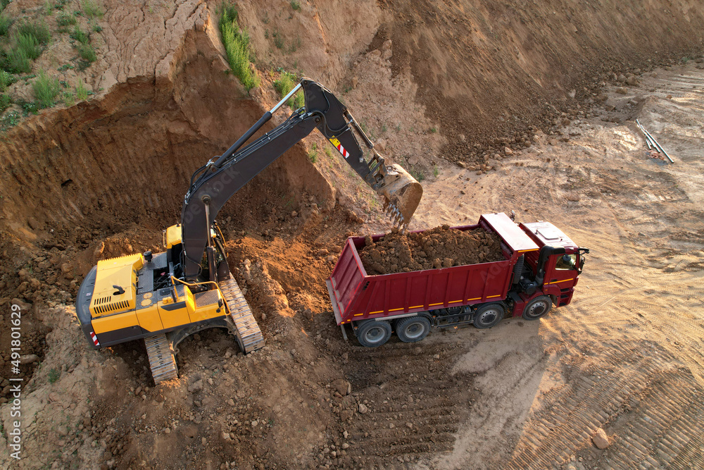 Earthmoving at construction site. Excavator load soil in dump truck ...