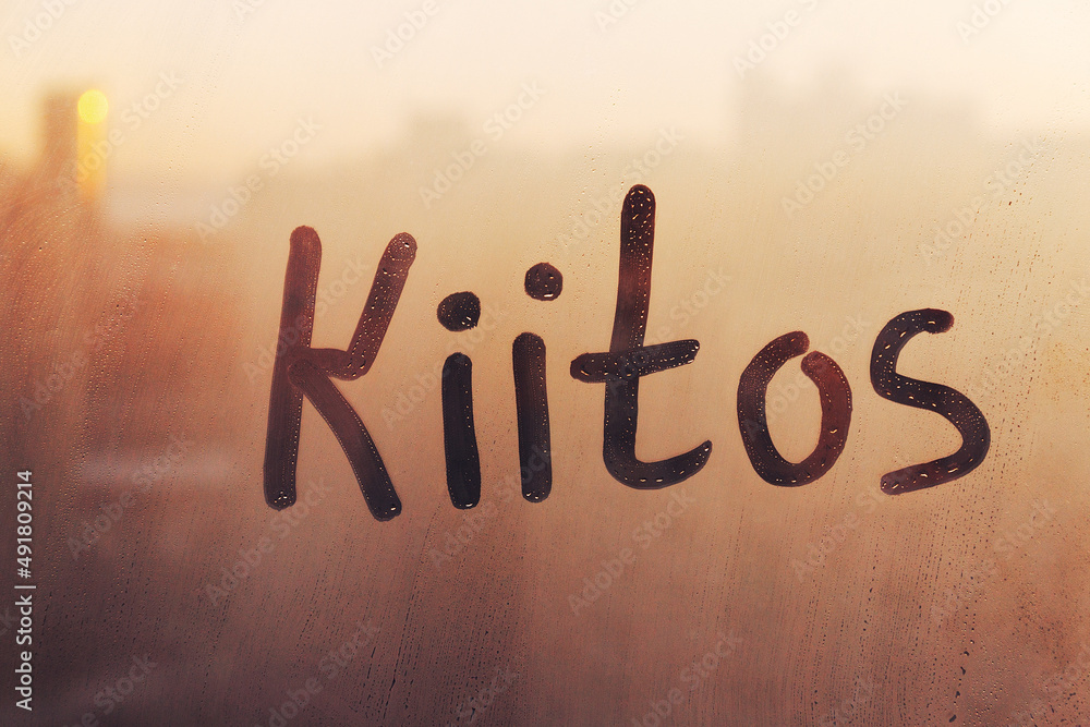 Finnish word Kiitos thanks in english are painted on wet orange sunrise ...