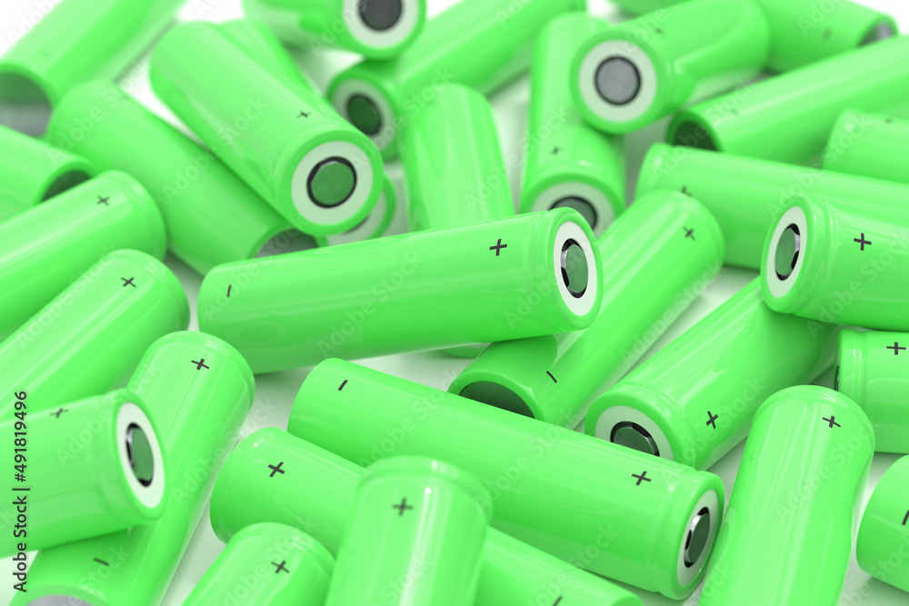 Lots of green cylindrical rechargeable batteries on a white table ...