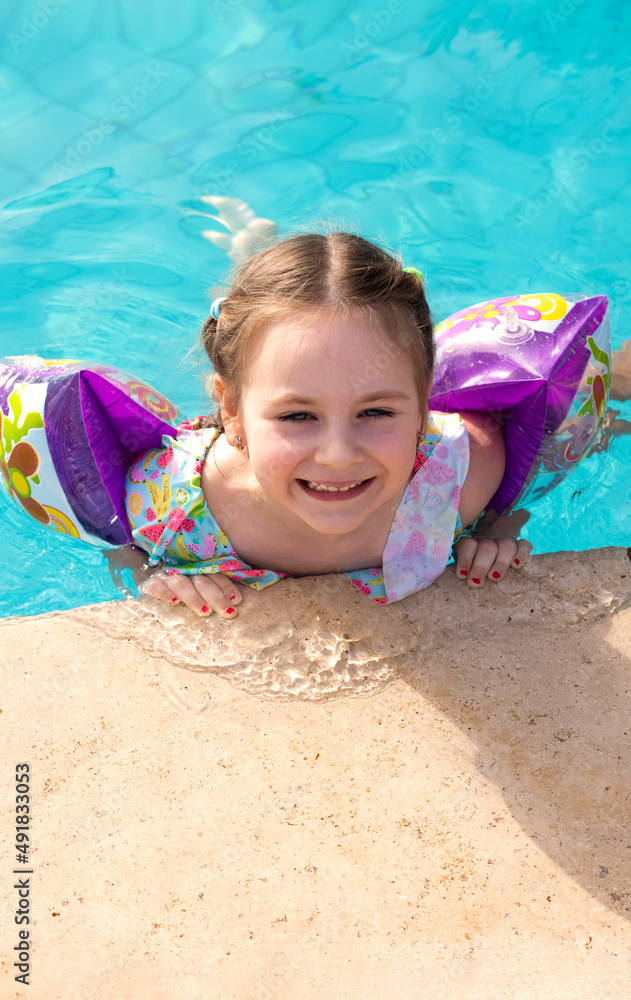 baby girl floating in the pool inflatable over-sleeves. holding on to ...