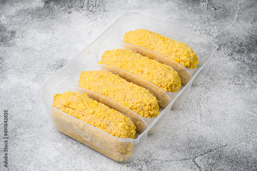 Breaded chicken patty, in plastic market container, on gray stone table ...