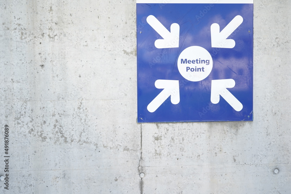 Metal shield saying meeting point attached on a concrete wall. The ...