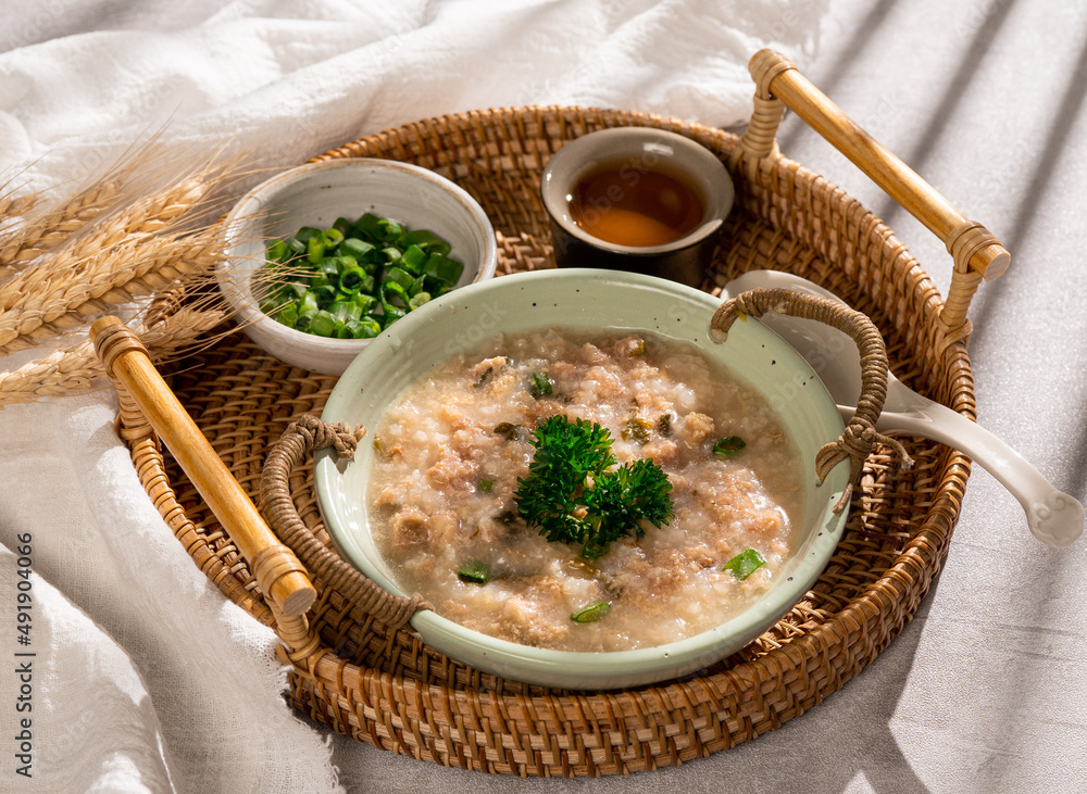 Congee minced beef congee with spring onion in a dish side view on grey ...