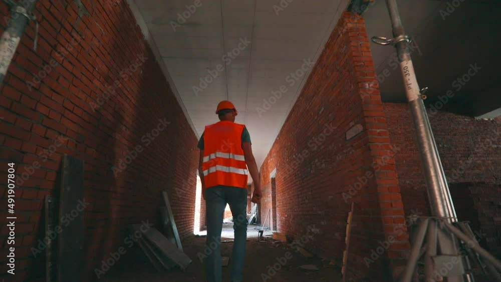 Builder inside the house. The builder goes inside the building under ...