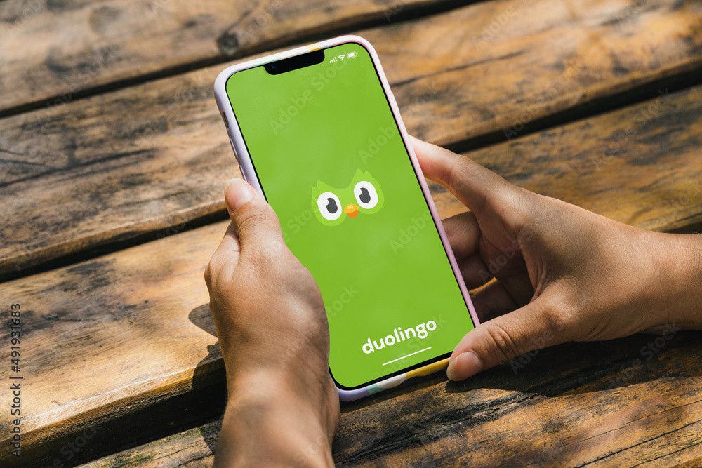 Girl in the park holding a smartphone with Duolingo language-learning ...