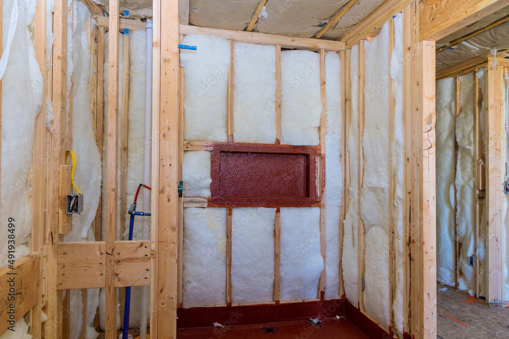 Installation of heating insulation on the wall, amongst wooden beams ...