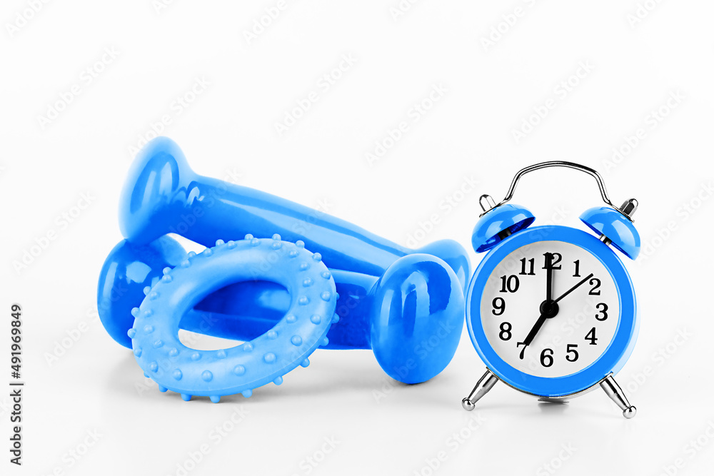 Time to do fitness. Blue alarm clock, dumbbells and round rubber ...
