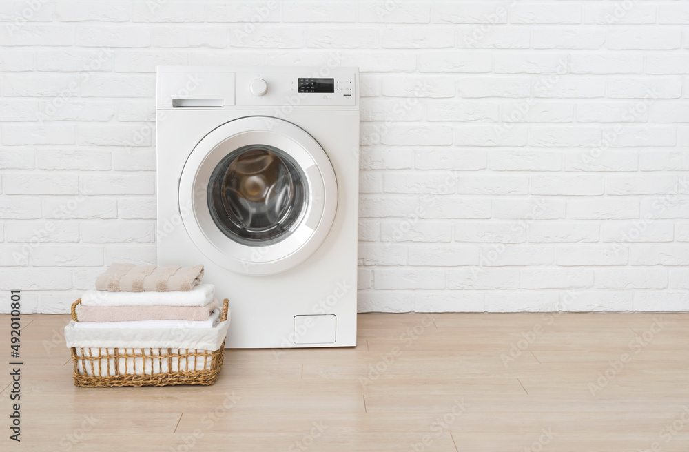 Washing machine and laundry basket on white brick wall background Stock ...