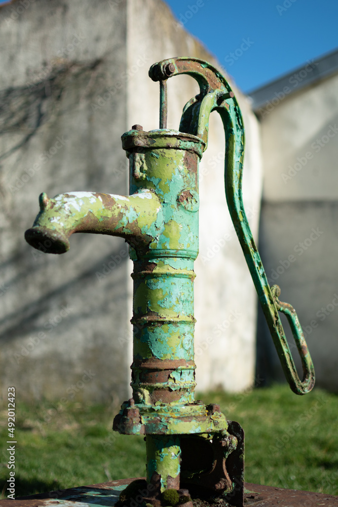 Old hand water pump on a well in the garden, watering and saving water ...