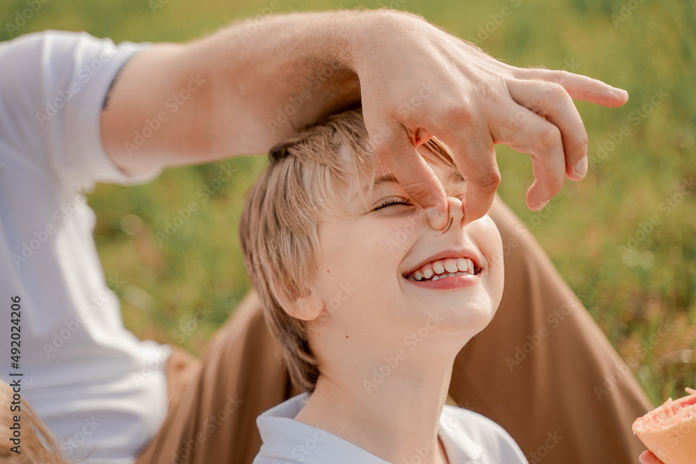 Father plays with his son pinching his nose during family walk through ...