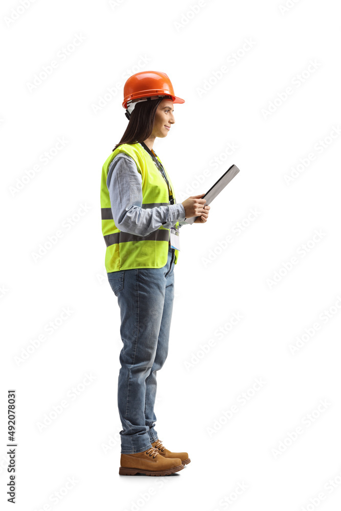 Full length profile shot of a young female engineer with a safety vest ...