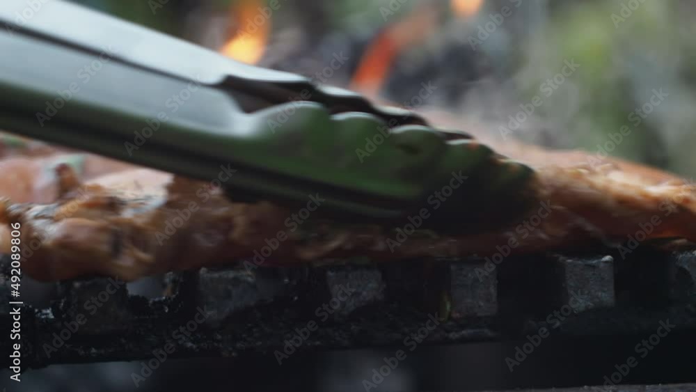cooking chicken fillet on the grill. the cook turns the fillet slices ...