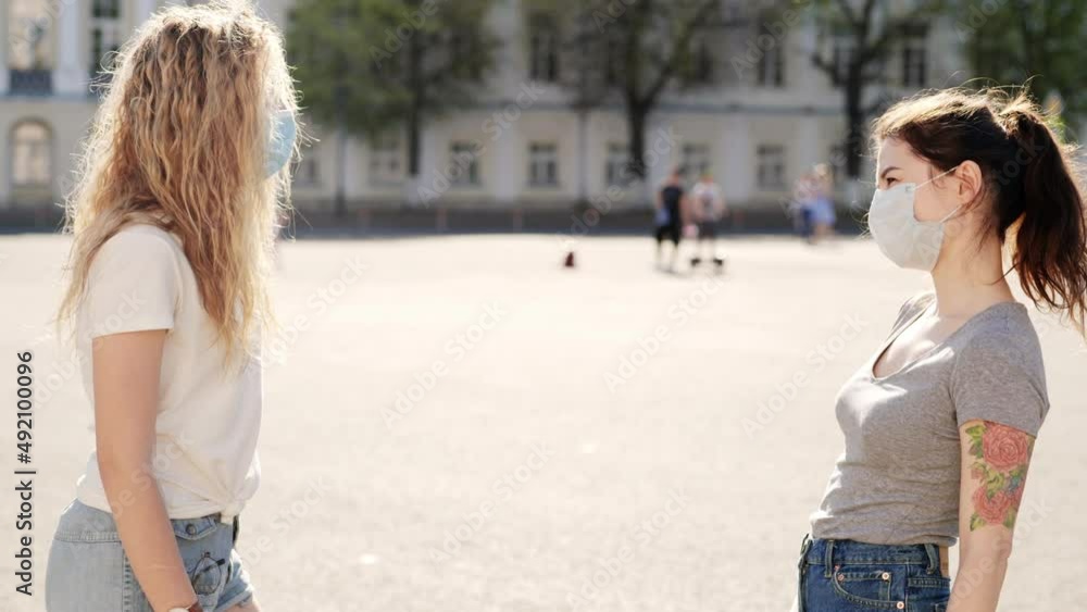 Two nice girls in protective medical mask meet at street during ...