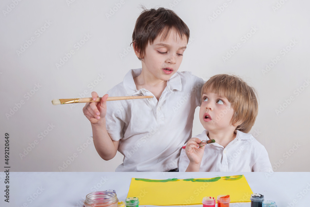 Two children draw together. The senior teaches the junior to draw. The ...