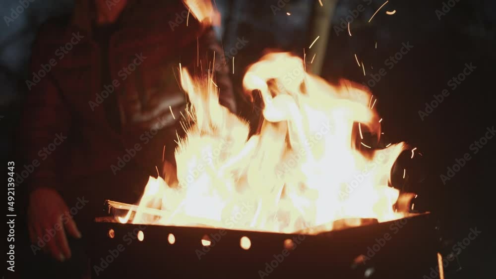 A bright orange fire burns in a metal brazier at night. Tourist hike ...