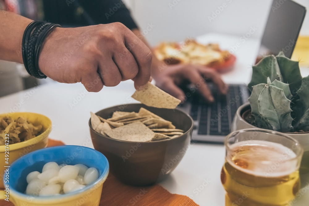 Hand taking finger food using laptop computer. Table with many foods ...
