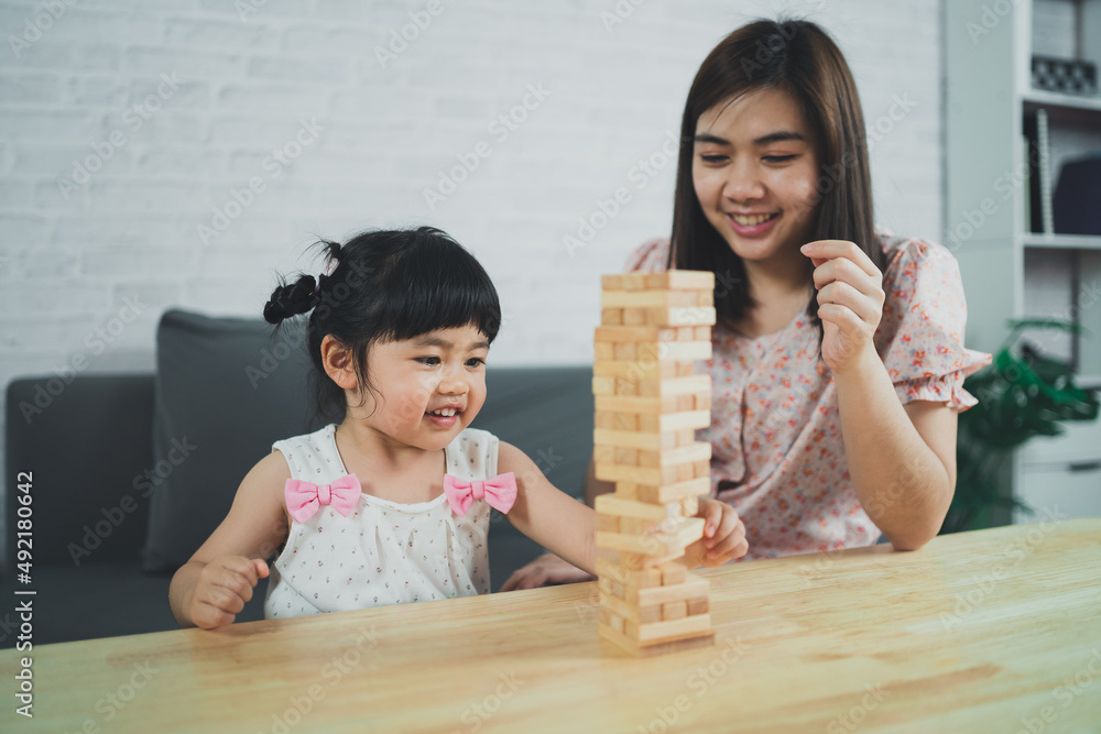 Foto de Jenga games concept. Asian daughter and mother smiling happily ...