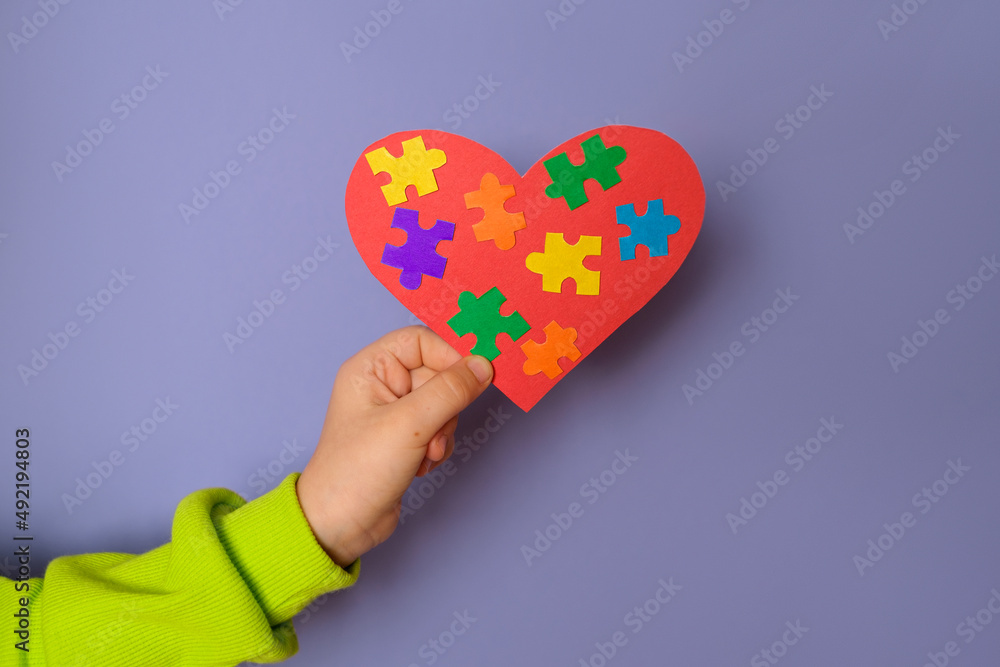 A big red heart with details of colored puzzles inside in a child's ...
