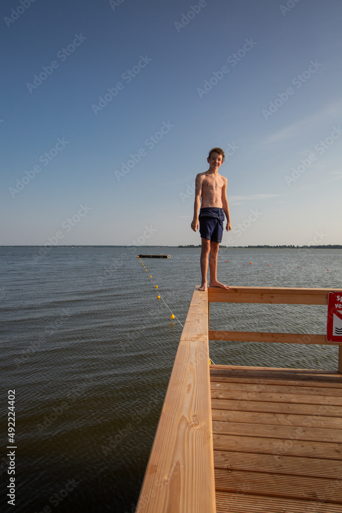 Teenage boy is standing at the parapet of a pier Stock Photo | Adobe Stock