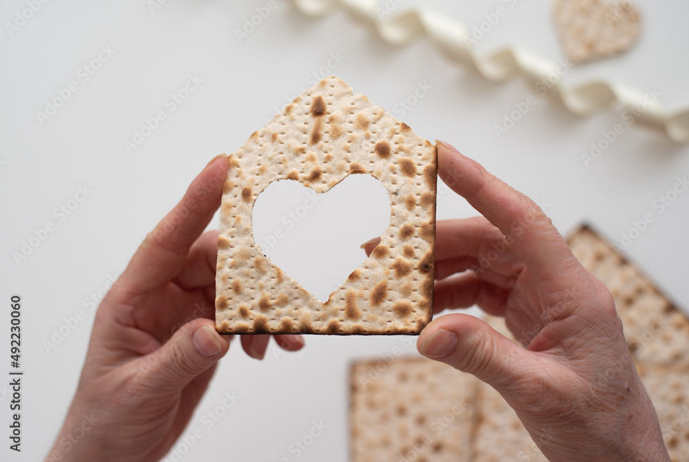Woman's hand holds Matzah shape of house with heart. Traditional of ...