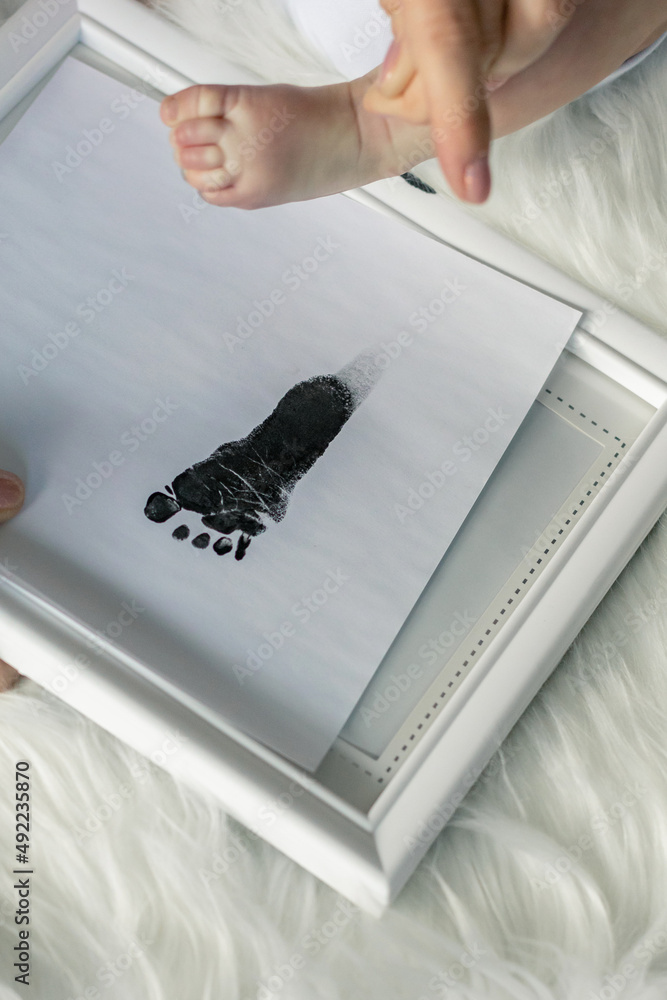 Baby footprints on white paper. Black footprint. The process of ...