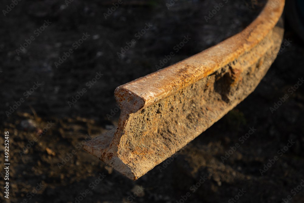 Closeup of rusted railway track, with end view of track rail and the ...