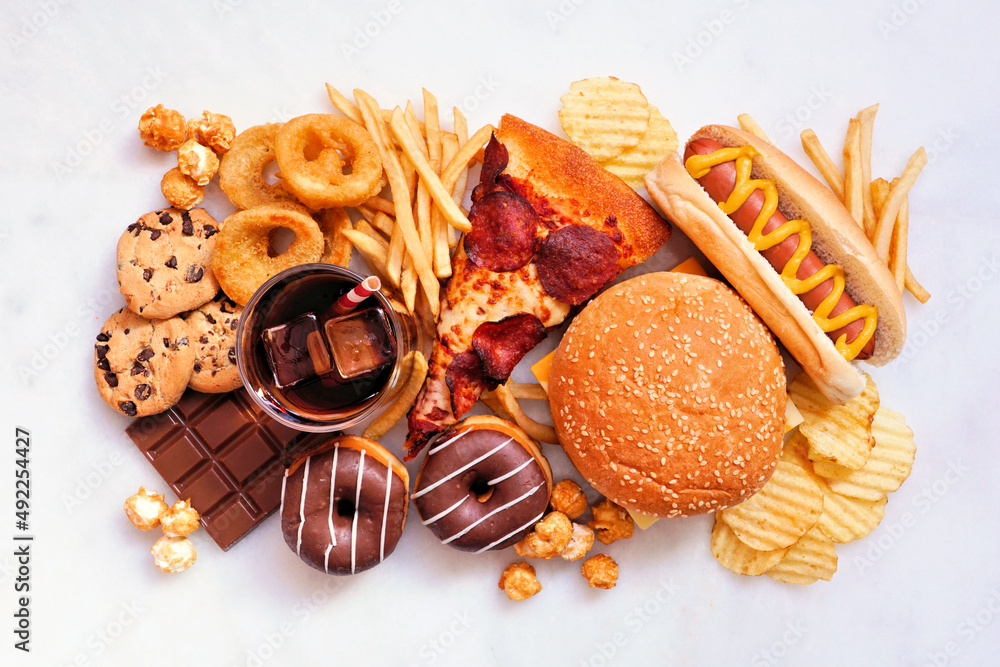 Junk food table scene. Collection scattered over a white marble ...