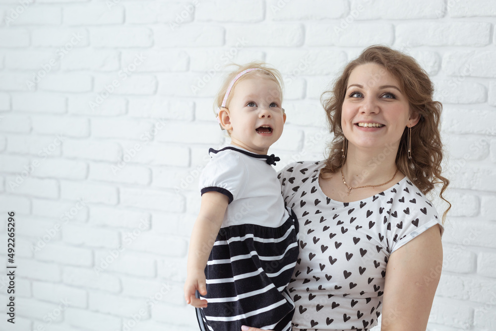 Mother holds her child with hearing aids and cochlear implants on white ...