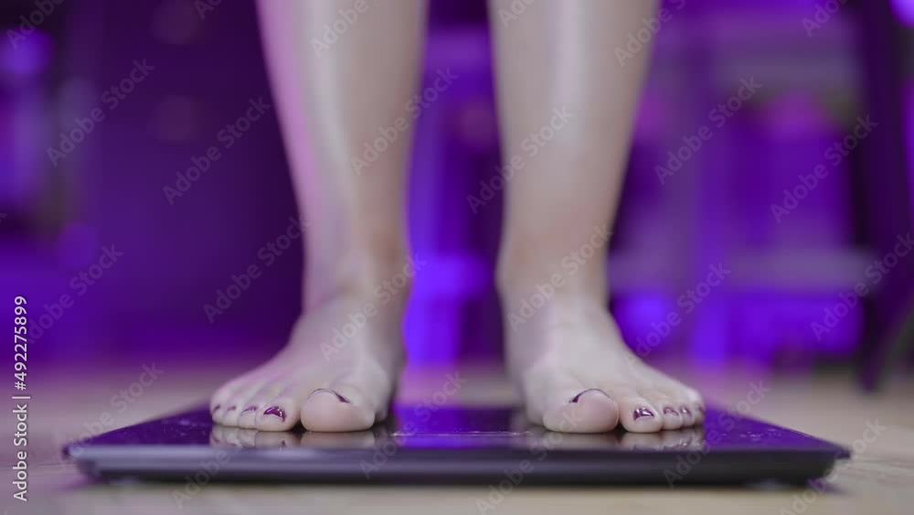 Female feet step on scale to measure weight with purple background 4K ...