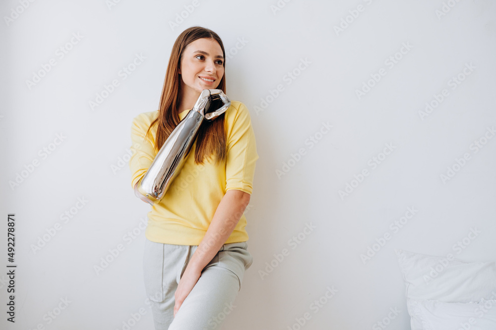 Pretty smiling blonde young woman with elegant bionic prosthesis arm ...