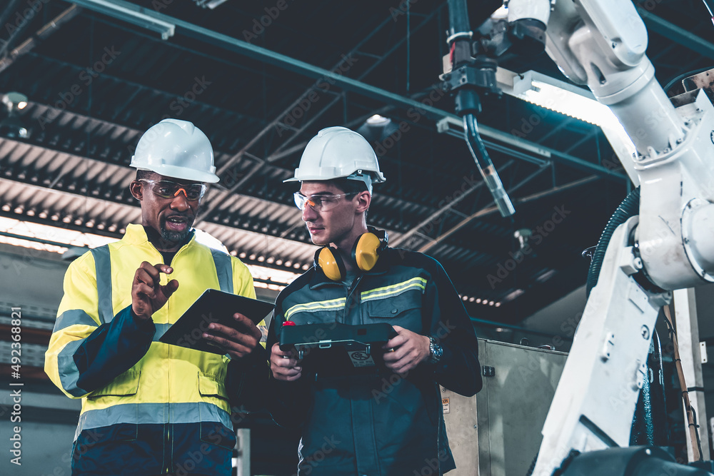 Factory workers working with adept robotic arm in a workshop . Industry ...