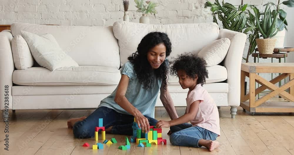 Young Afro American mother play constructor on warm heated floor with ...