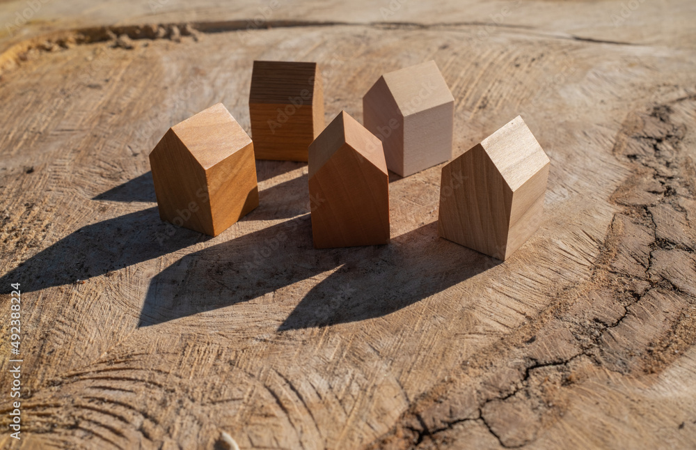 wooden house models on tree stump in the outdoors. concept image for ...
