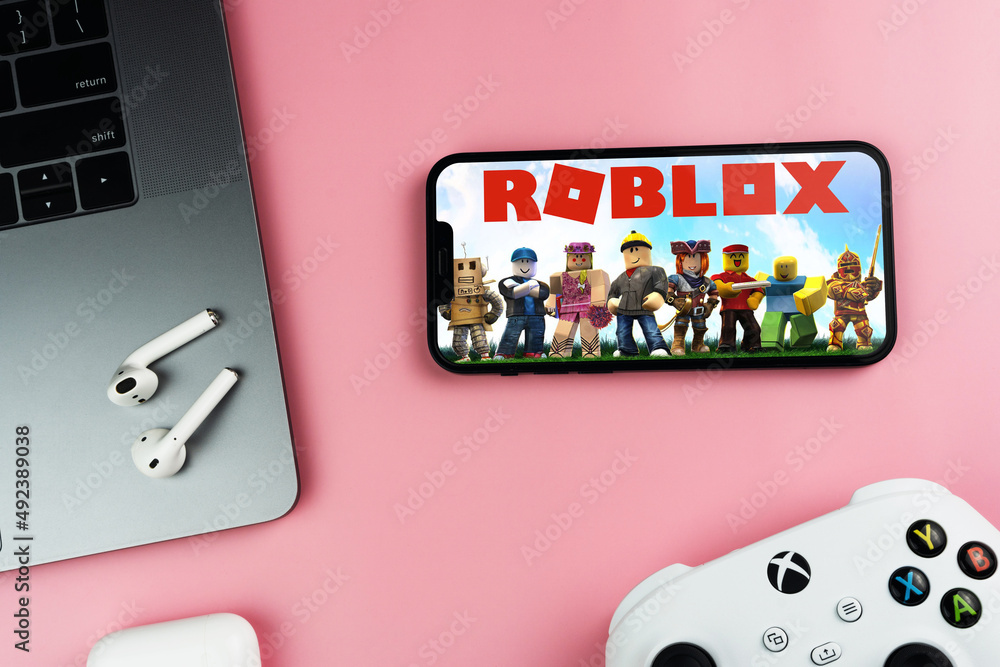 Roblox mobile game app on the smartphone screen. Pink background with ...