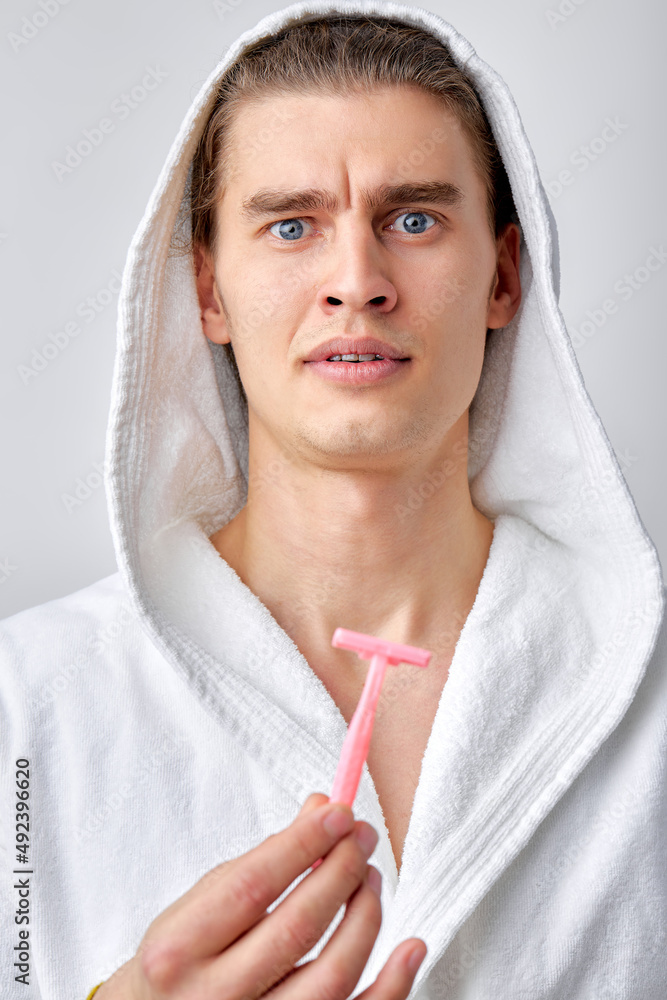 Handsome young man in bathrobe isolated. Portrait of confused strong ...