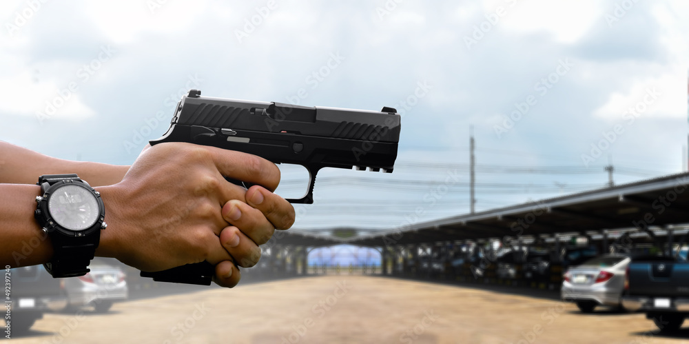 9mm automatic pistol holding in hands of shooter, blurred supermarket ...