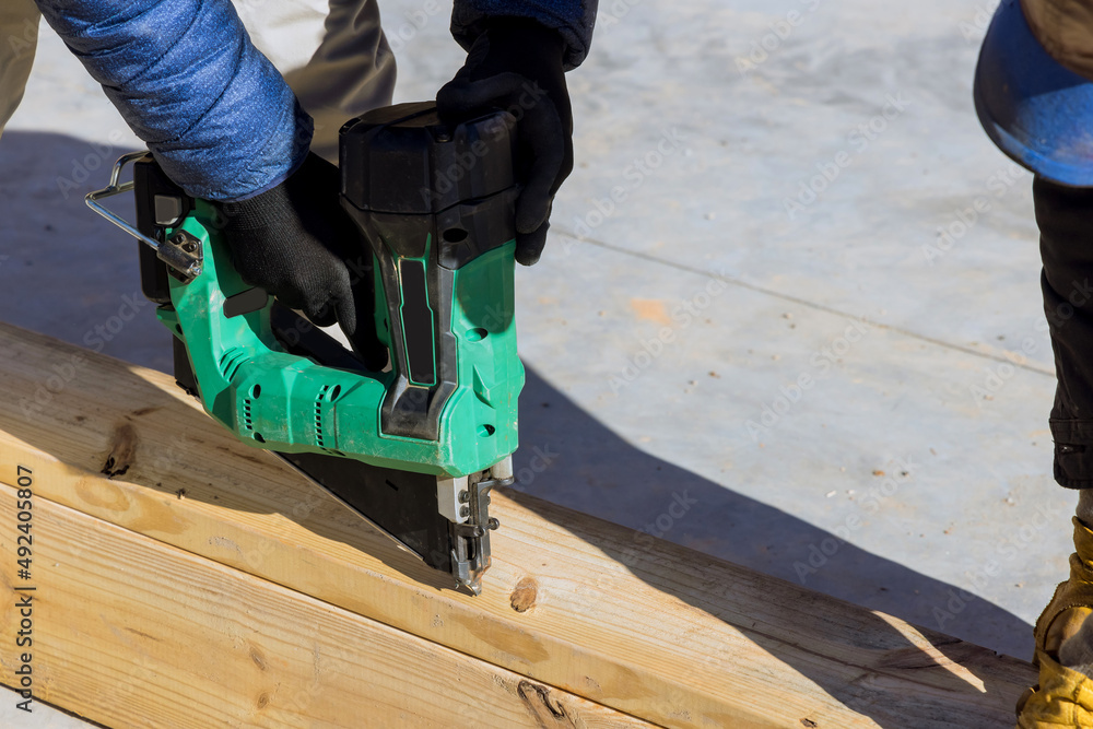 Builder inside wooden houseman in nailing wooden beams works for ...