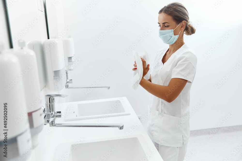 Hygiene, health care. Portrait of female doctor or nurse drying hands ...