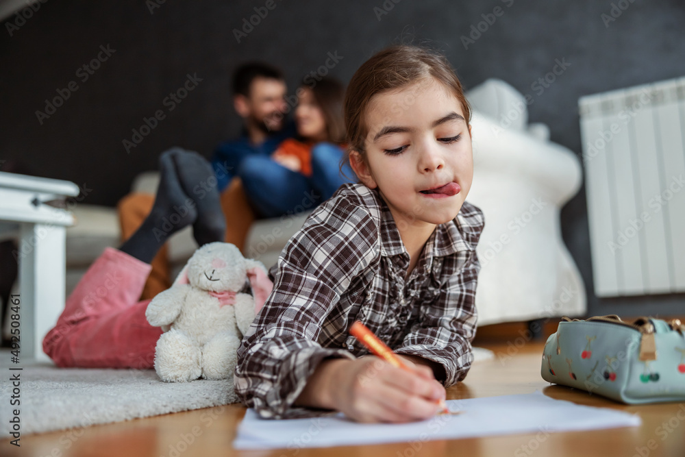 Child lying down on stomach on the floor drawing. Stock Photo | Adobe Stock