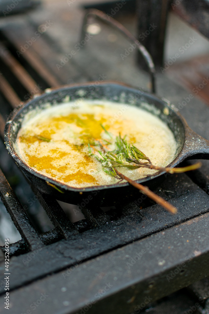 mantequilla derretida con romero en sarten de hierro sobre la parrilla ...