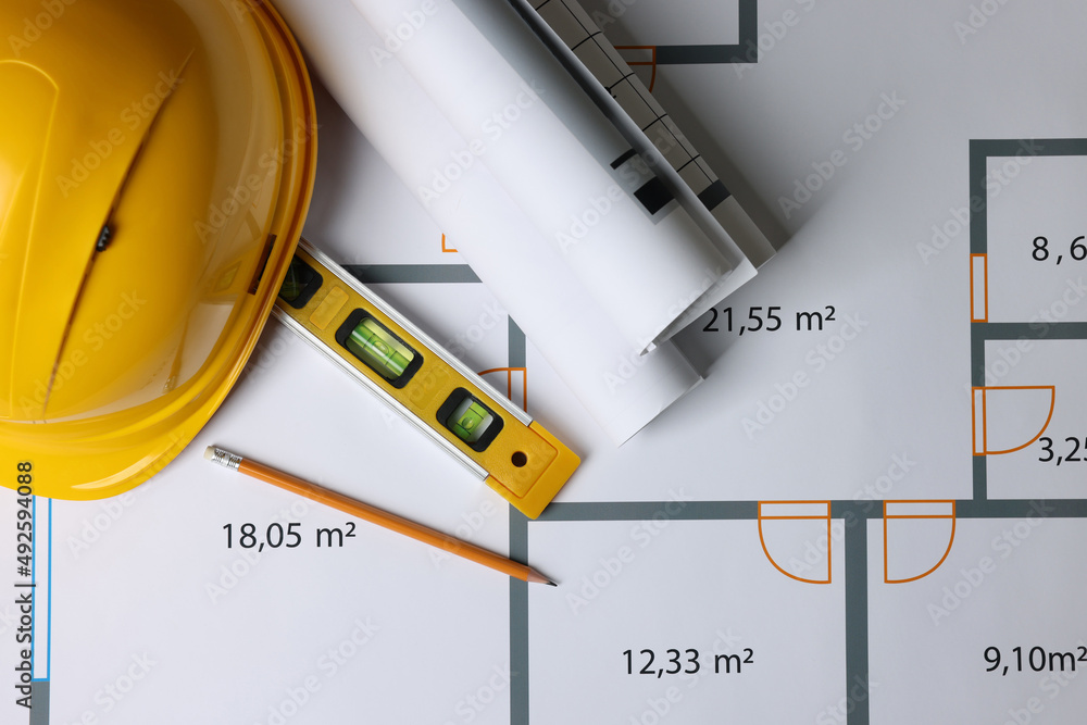 Rolled construction drawings, safety hat, pencil and bubble level on ...